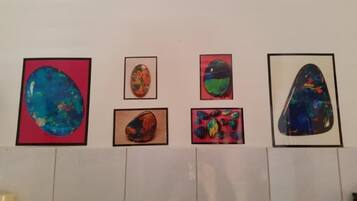 Uma parede com seis obras de arte emolduradas, de diferentes formatos e cores.