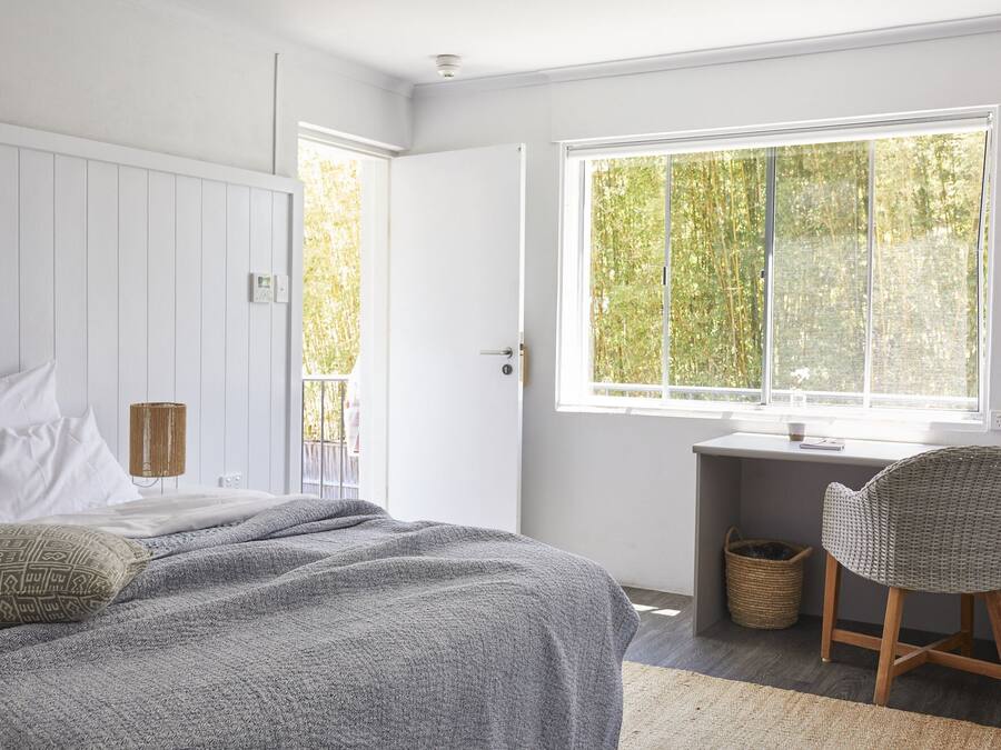 Quarto com cama, escrivaninha e cadeira.