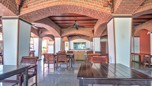 Uma ampla sala de jantar com arcos de tijolo, mesas e cadeiras de madeira.