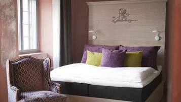 Quarto com cama, uma cadeira e mesa de cabeceira.