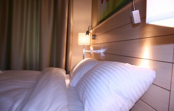 Quarto de hotel com uma cama, uma mesa de cabeceira e um abajur.