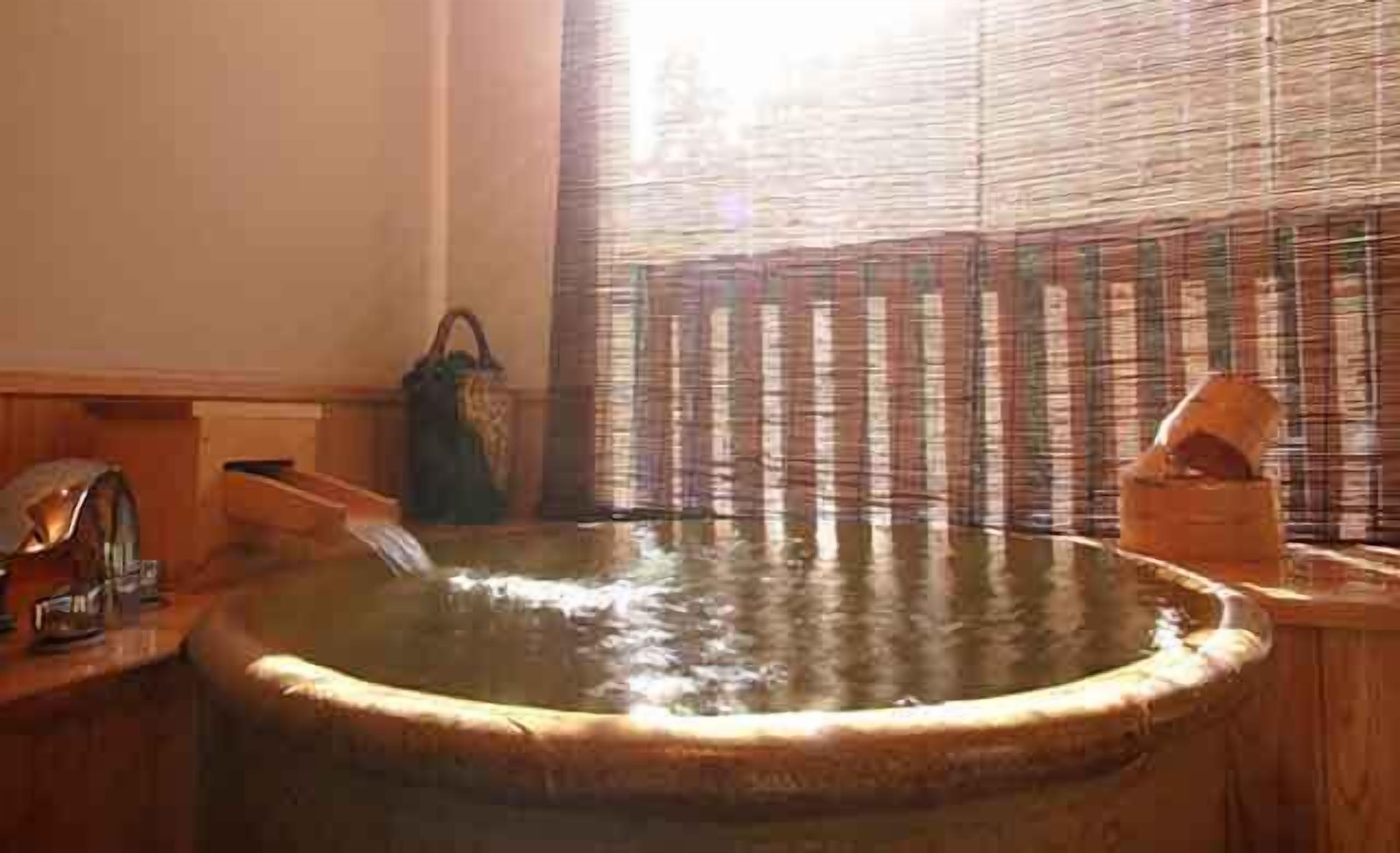 Uma banheira de hidromassagem em um quarto com um banco de madeira e uma janela com persianas.