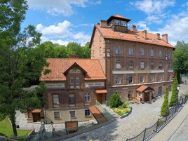 Um hotel de vários andares com telhado de telhas vermelhas, fachada de tijolo e uma pequena estrutura semelhante a uma torre no topo.