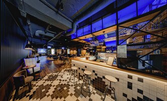 Uma área de bar com banquetas, balcão e piso revestido de azulejos.