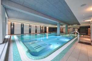 Piscina interior com água cristalina, bordas azulejadas e design moderno.