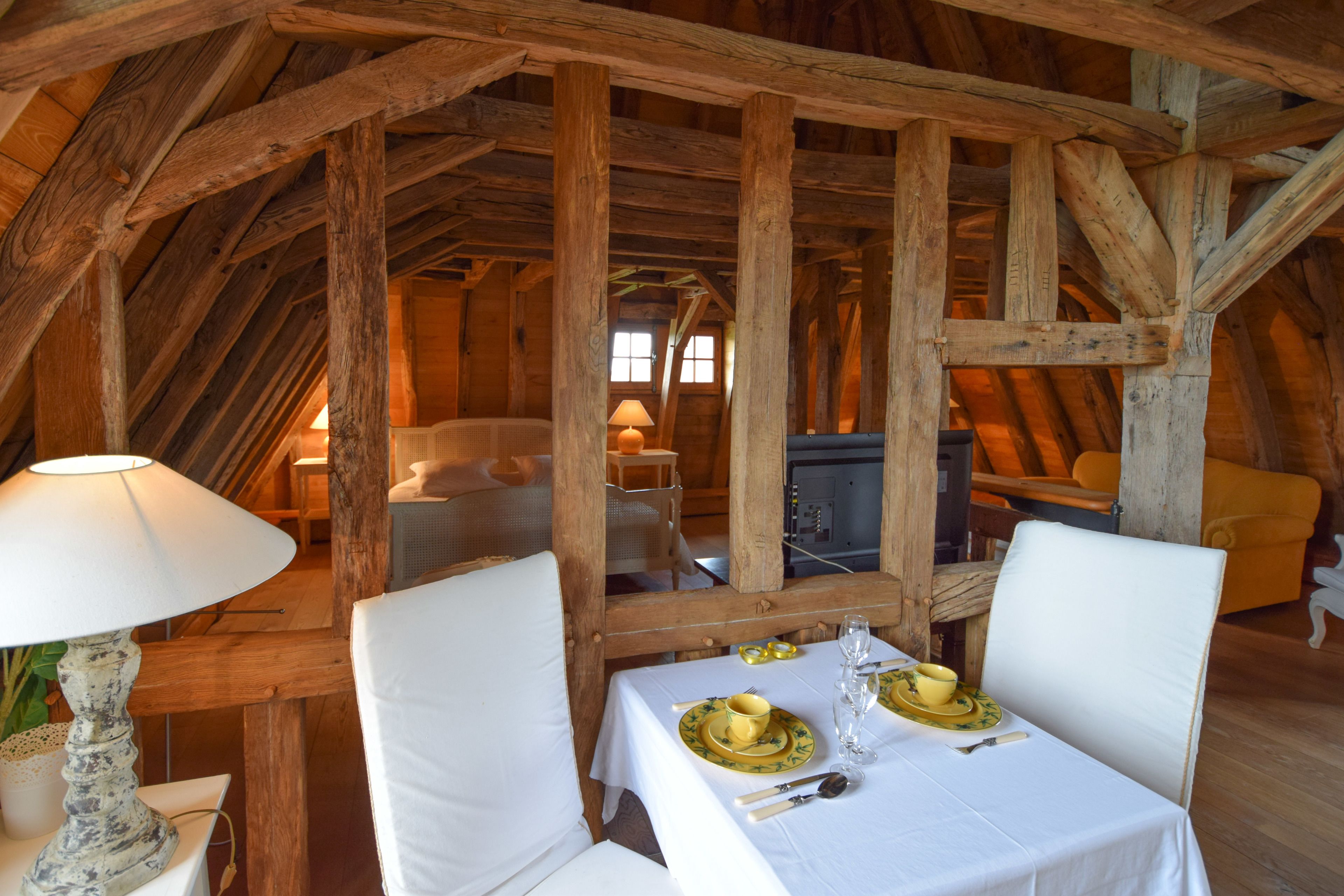 Uma sala de jantar com uma mesa posta para dois, vigas de madeira e vista para o interior.