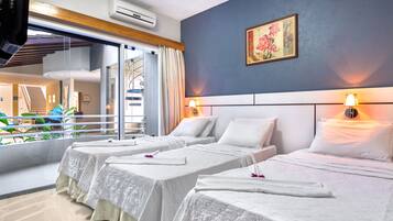Quarto de hotel com duas camas, uma janela grande com vista para uma piscina e um quadro na parede.