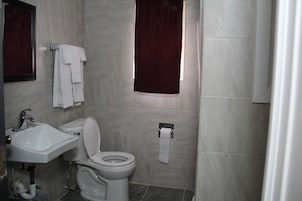 Casa de banho com sanita, lavatório e suporte para toalhas.