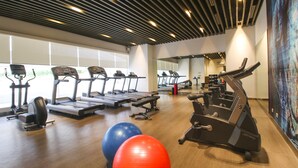 Uma academia com esteiras, elípticos e bolas de exercício.