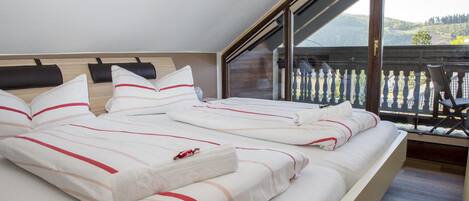 Quarto de hotel com duas camas, varanda e vista para o campo, e cabeceira de madeira.