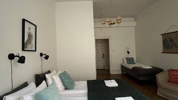 Quarto de hotel com uma cama grande, uma cama menor, um sofá e uma escrivaninha.