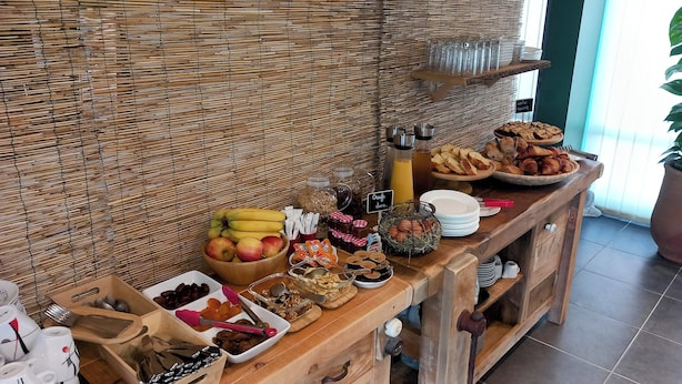 Mesa de buffet com diversos alimentos e utensílios, incluindo frutas, doces e acompanhamentos.