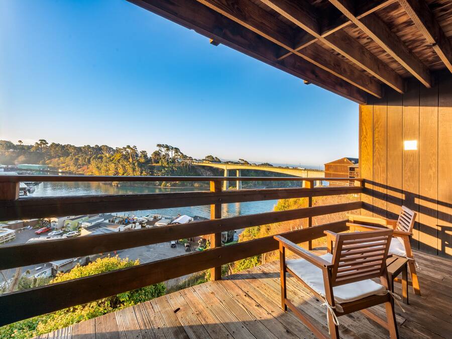 Um deck de madeira com vista para um rio e colinas ao longe.