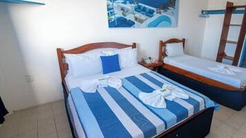 Quarto de hotel com duas camas, um quadro de uma paisagem costeira e uma escada de madeira.