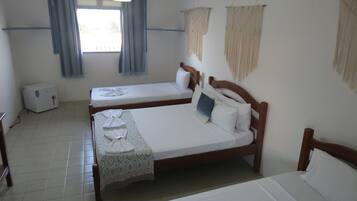 Quarto com duas camas de solteiro, uma mesinha, aquecedor e janela com cortinas.