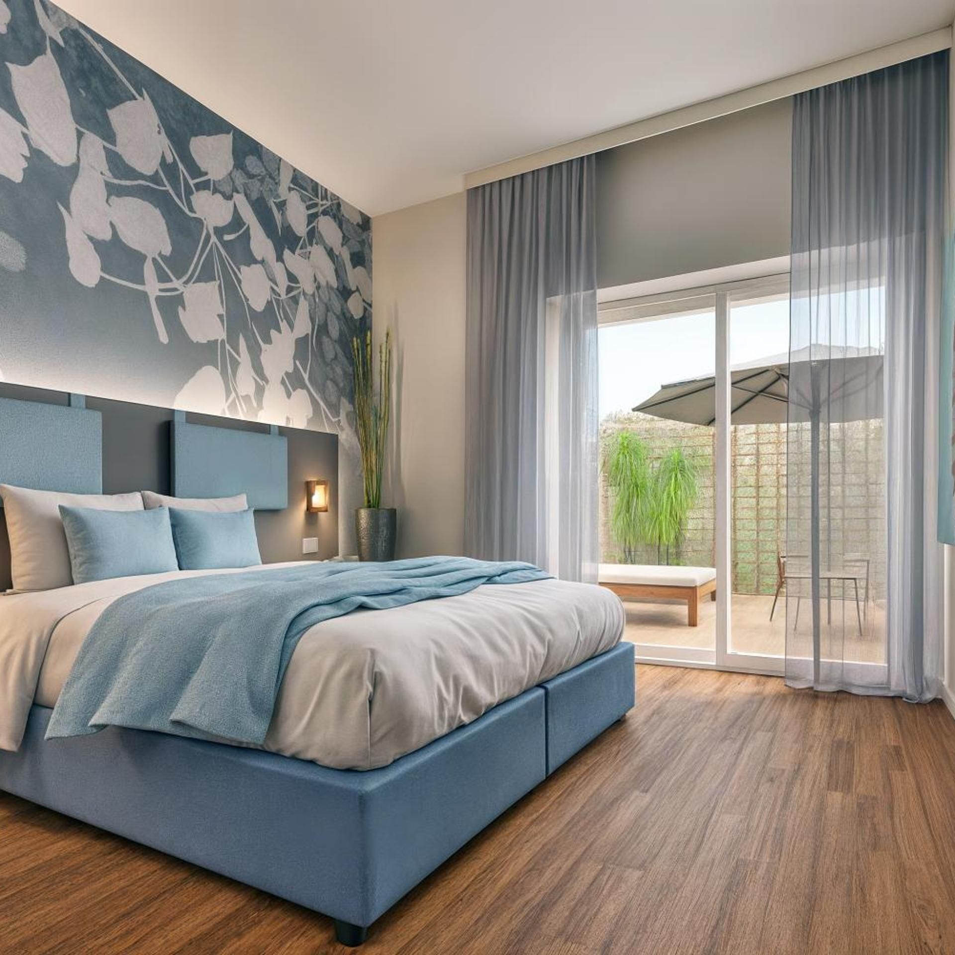 Quarto moderno com cama grande, cabeceira fixada na parede e porta de vidro deslizante para um pátio.