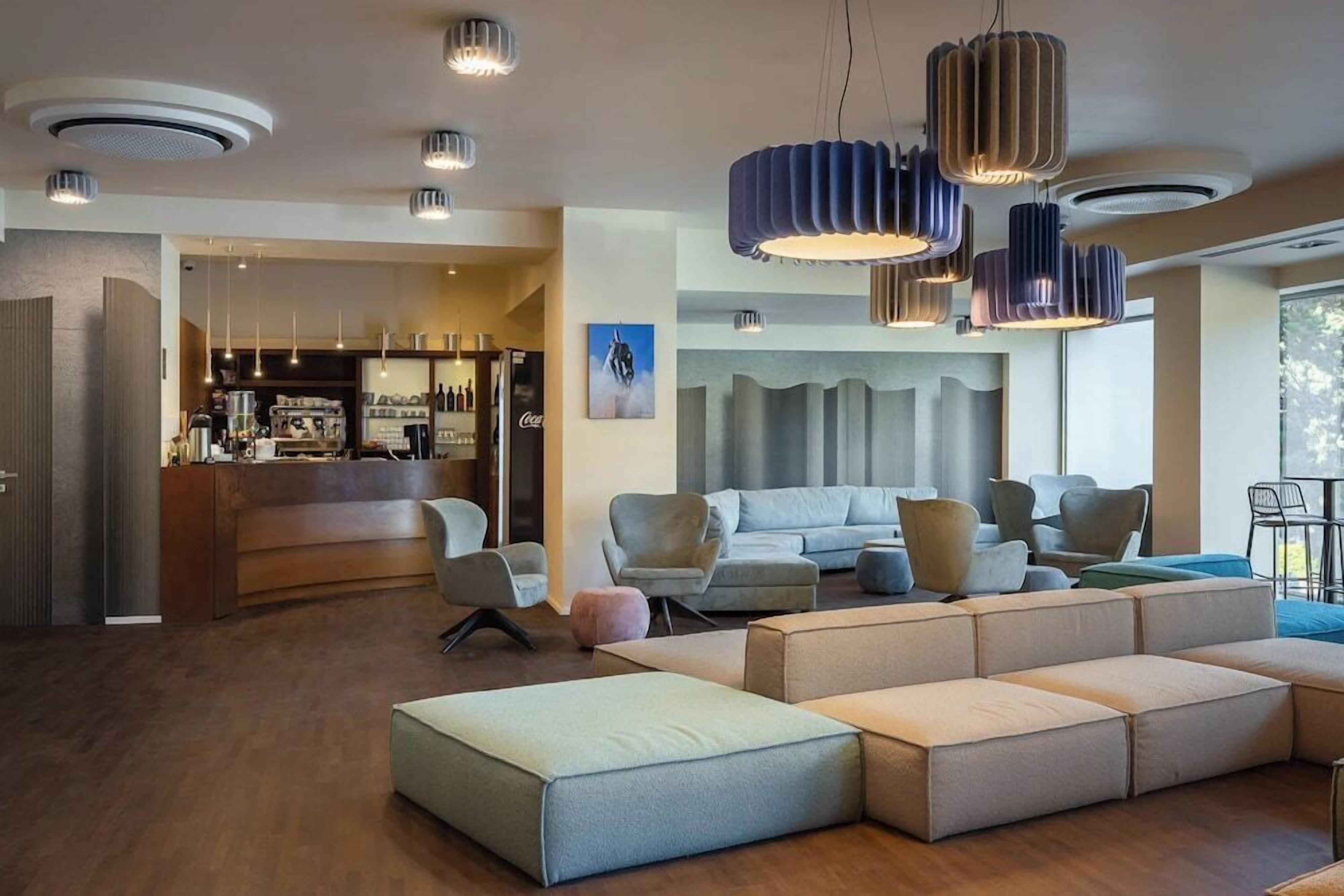 Uma sala de estar moderna com um sofá seccional, pufes e um espaço de bar com geladeira e prateleiras.