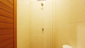 Um pequeno espaço de chuveiro com azulejos e um toalete à direita.