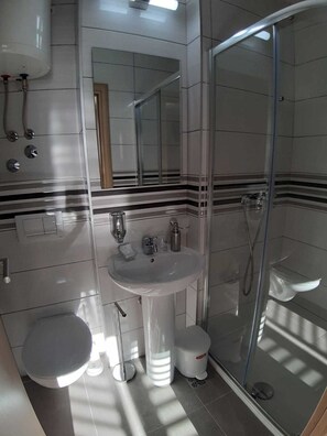 Uma casa de banho moderna com lavatório, sanita e cabine de duche em vidro.