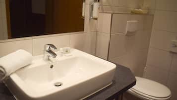 Um banheiro com pia branca, espelho, vaso sanitário e porta-toalhas.