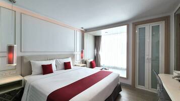 Quarto de hotel com uma cama grande, uma escrivaninha e um guarda-roupa.
