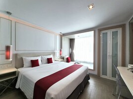 Quarto de hotel com uma cama grande, uma escrivaninha e um guarda-roupa.
