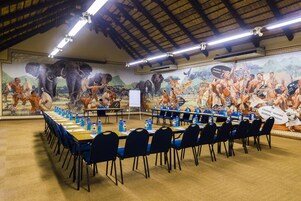 Uma sala de conferência com uma mesa comprida, cadeiras e garrafas de água.