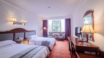 Quarto de hotel com duas camas, uma escrivaninha, uma cadeira, uma televisão e uma janela com cortinas.