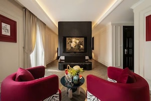 Uma sala de estar moderna com lareira, dois poltronas vermelhas e uma mesa de centro com objetos decorativos.