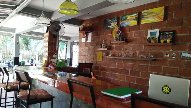 Uma área de bar com paredes de tijolo, cadeiras de madeira e um balcão com um laptop.