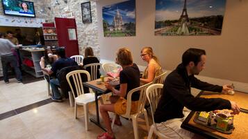 Restaurante com cadeiras e mesas brancas, e uma parede de pedra.