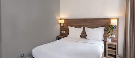Cama bem arrumada com lençóis brancos em um quarto de hotel moderno.