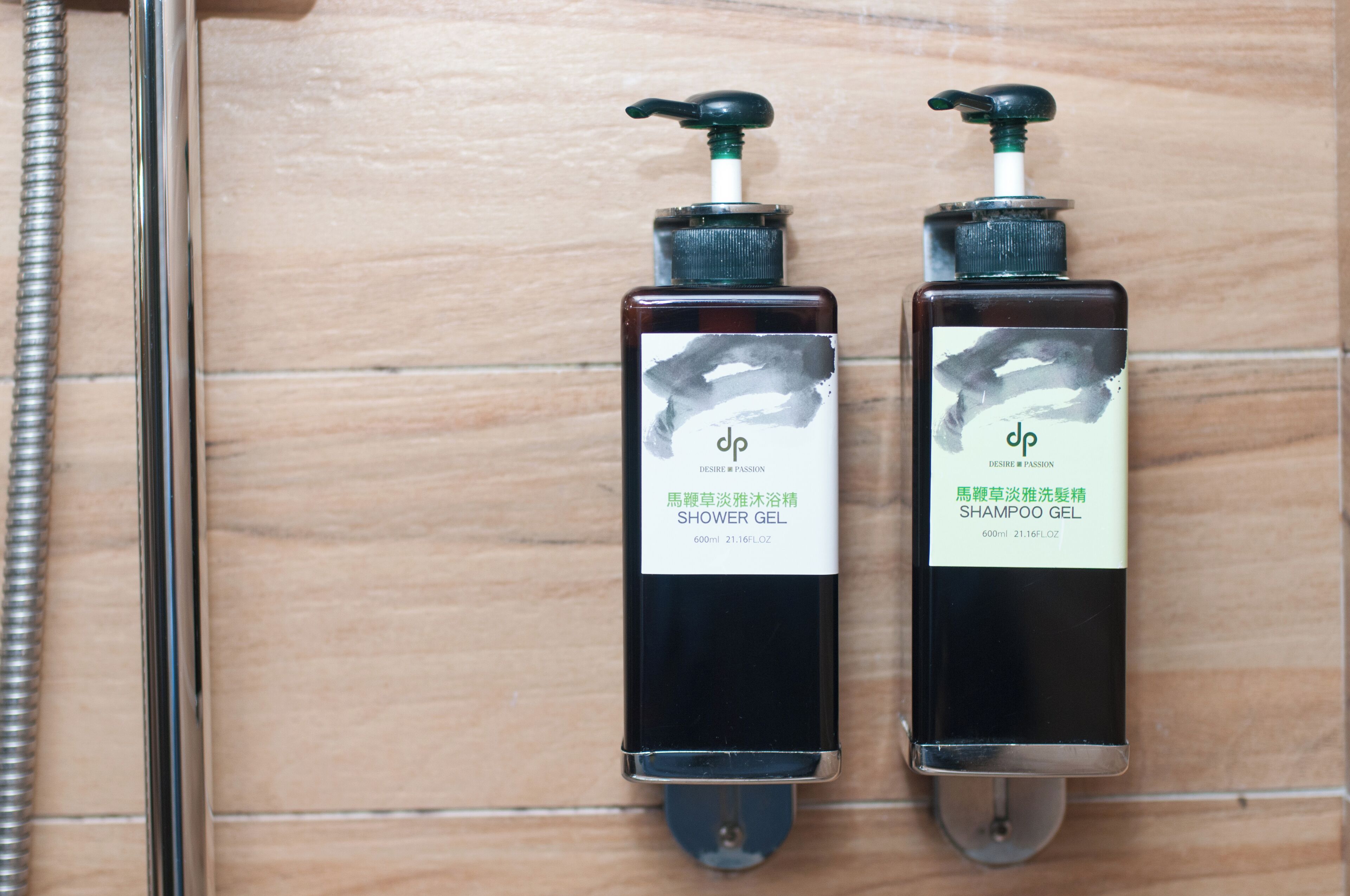 Dois frascos de gel de banho e shampoo em uma parede revestida de azulejos.