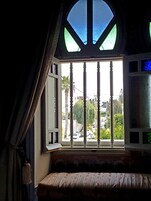 Quarto com uma grande janela com design de vidro decorativo, um banco e vista para a rua.