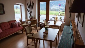 Uma sala de estar aconchegante com um sofá vermelho, uma mesa de jantar de madeira e um banco.