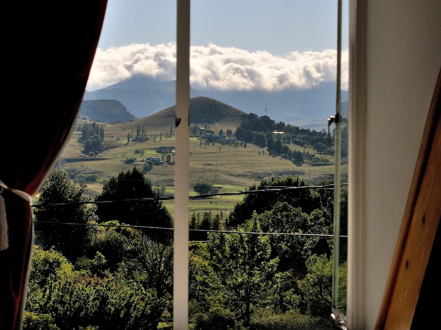 Janela com vista para uma paisagem, incluindo colinas e árvores.