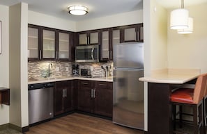Uma cozinha moderna com armários de madeira escura, eletrodomésticos de aço inoxidável e backsplash revestido de azulejos.
