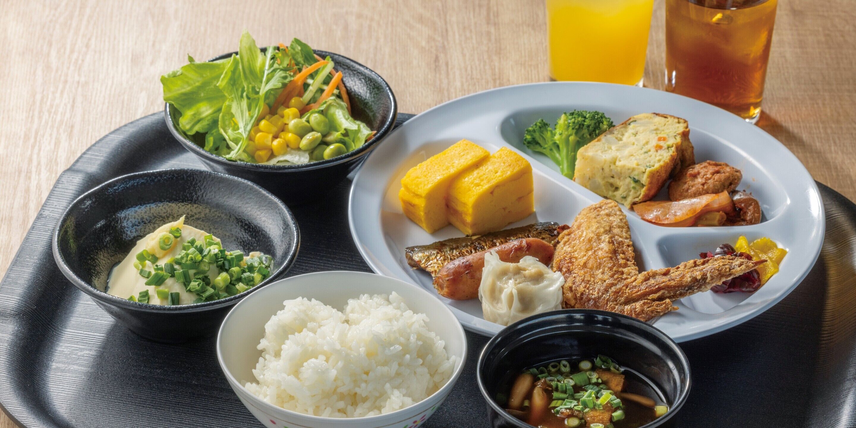 Uma bandeja com diversos pratos, incluindo arroz, legumes e um filé de peixe.