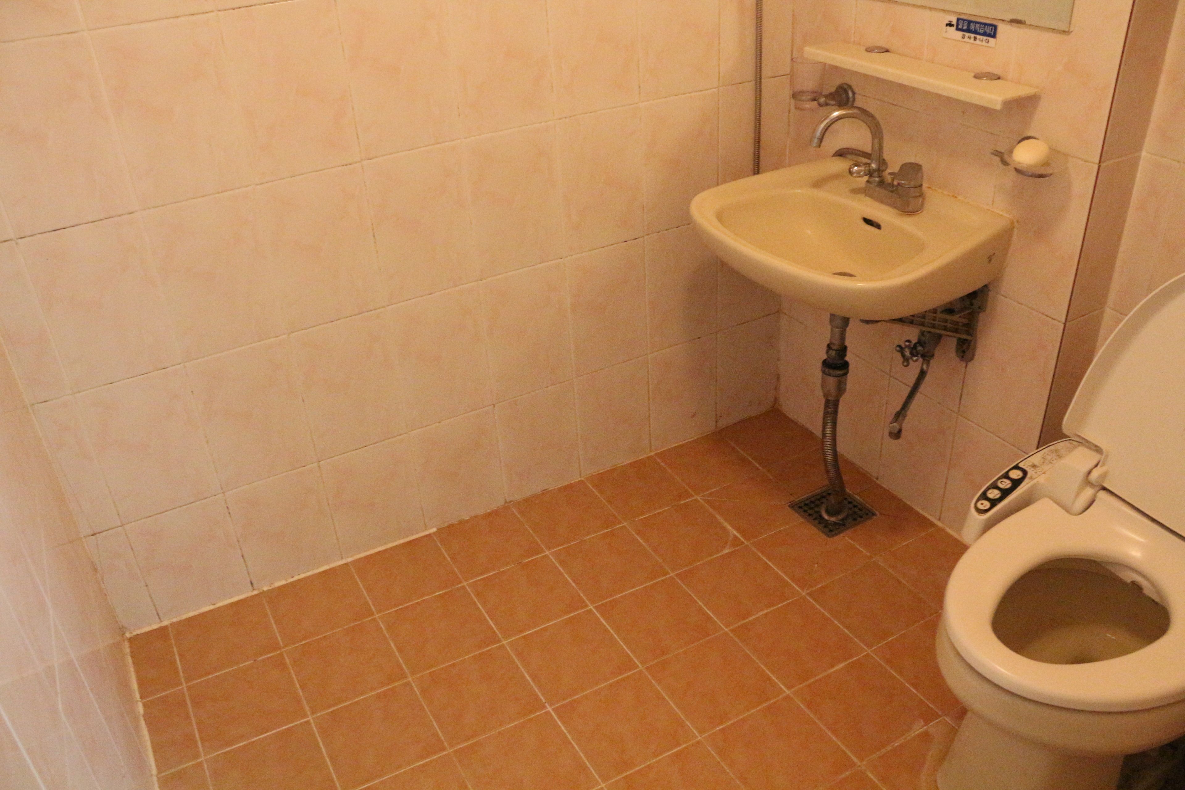 Um banheiro com pia, vaso sanitário e piso cerâmico.