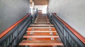 Uma escada com degraus de madeira e guarda-corpos pretos, que leva a um andar superior.