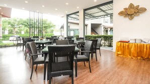 Uma área de refeições interna ampla, com pé direito alto, grandes janelas e vista para o exterior.