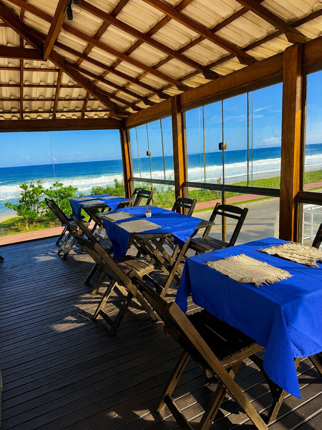Uma área de refeições ao ar livre coberta, com mesas e cadeiras, com vista para o oceano.