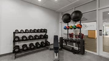 Uma academia com equipamentos de musculação, incluindo halteres e kettlebells.