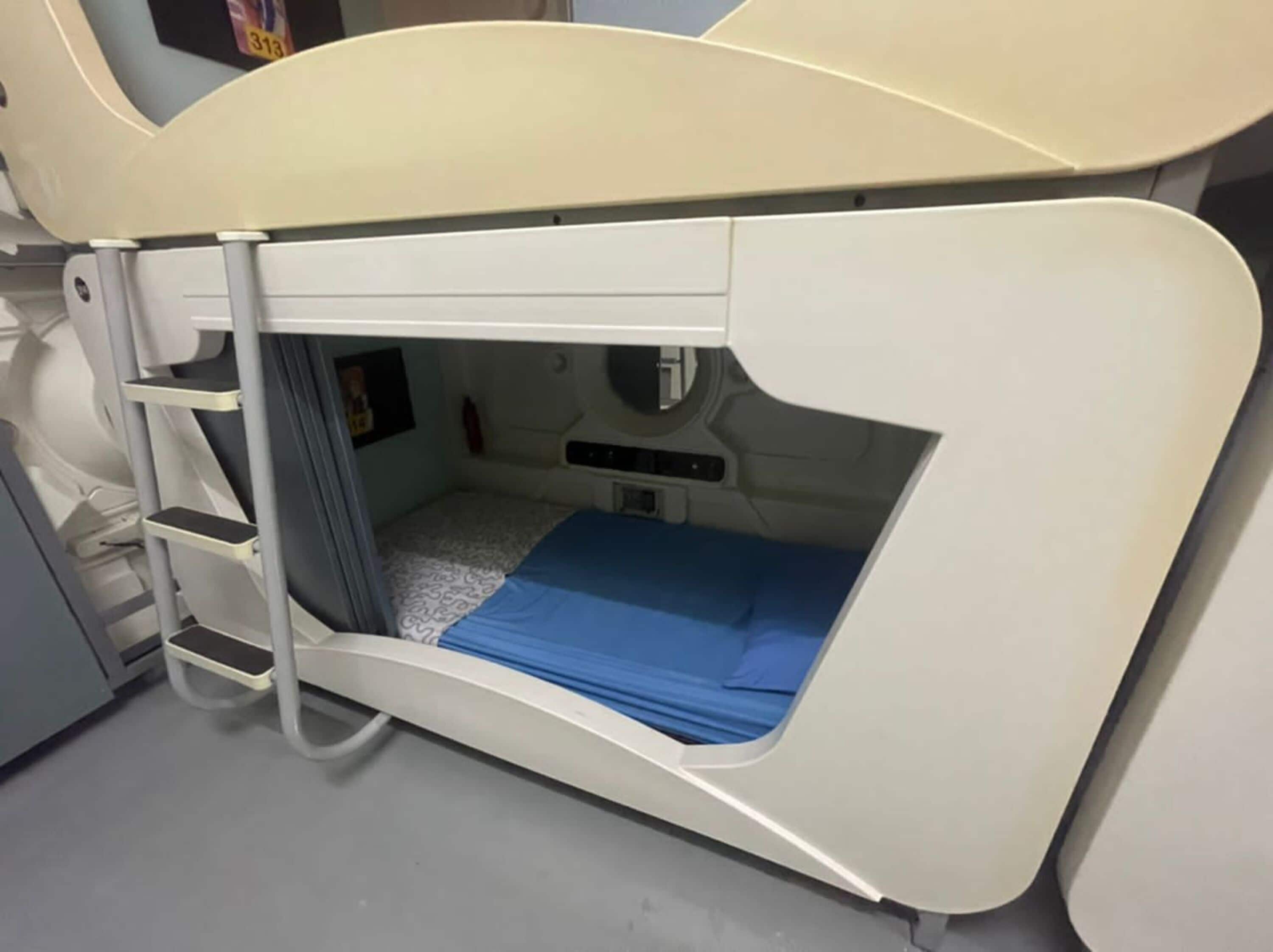 Uma cama beliche com escada, uma pequena prateleira e um painel de controle.