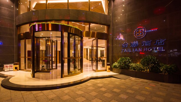 Entrada de hotel com porta giratória, portas de vidro e aviso de proibido fumar.