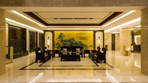Um lobby com balcão de recepção, área de estar e um grande mural na parede.