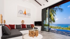Uma sala de estar moderna com um sofá grande, uma mesa de centro de vidro e um quadro de um templo.