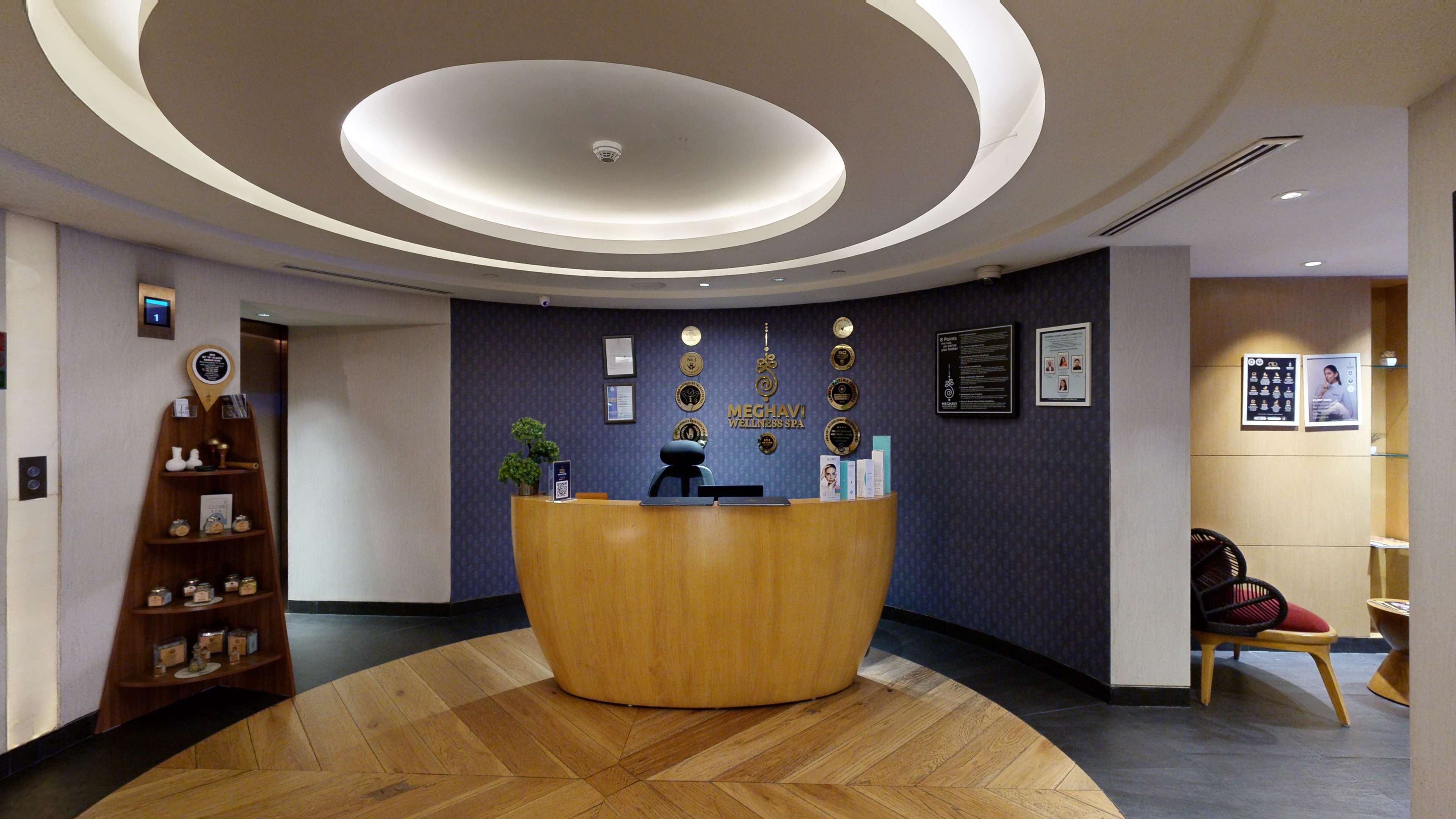 Uma área de recepção com um balcão de madeira, um display digital e uma parede decorada com certificados e placas.