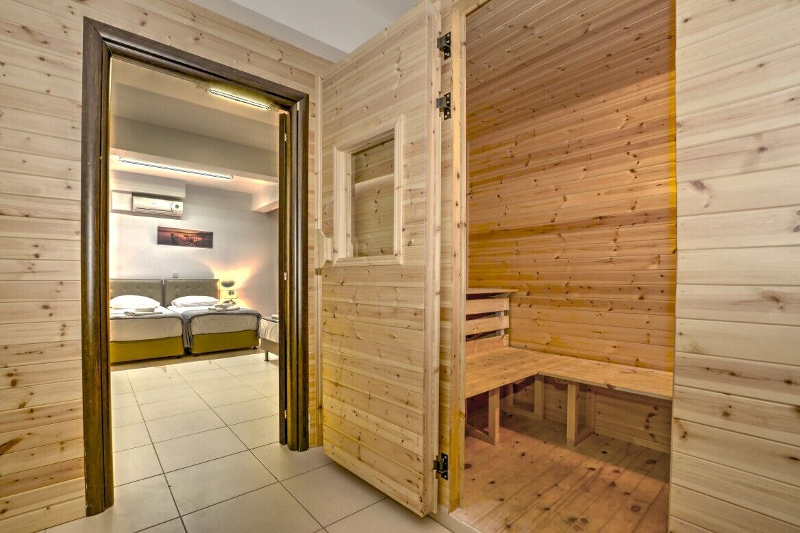 Interior de madeira com uma cama, um banco e uma área de sauna.