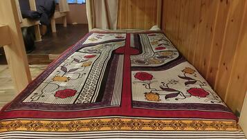 Quarto com piso de madeira, tapete estampado e cama com cabeceira.